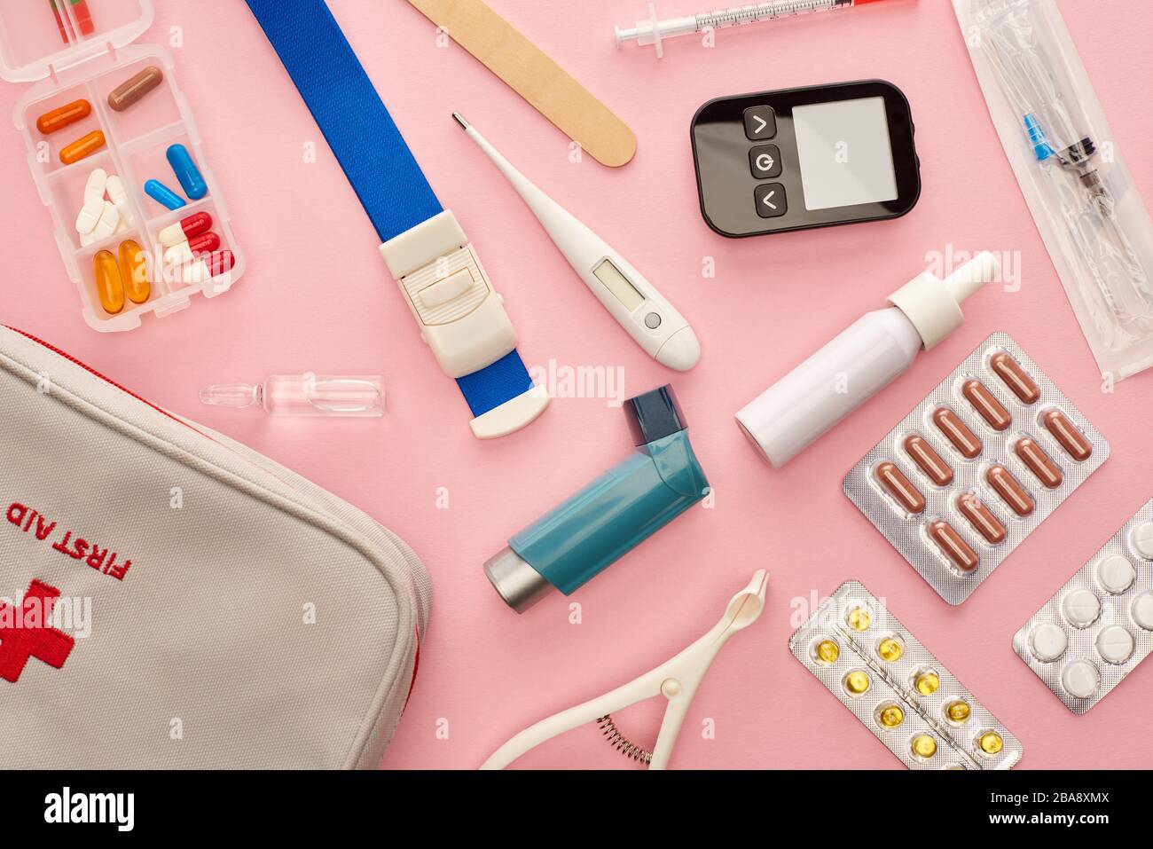 Top view of first aid kit, pills and medical objects on pink background ...