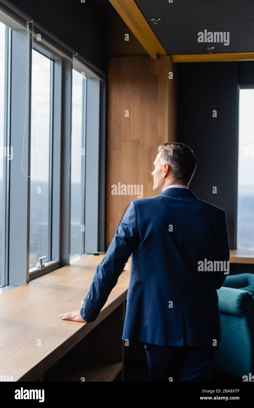 back view of businessman in suit looking through window Stock Photo - Alamy