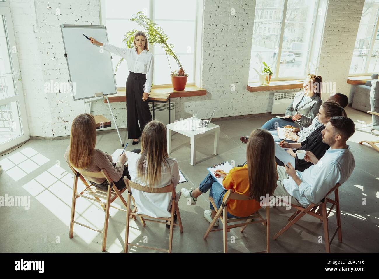 Giving information. Female speaker giving presentation in hall at ...