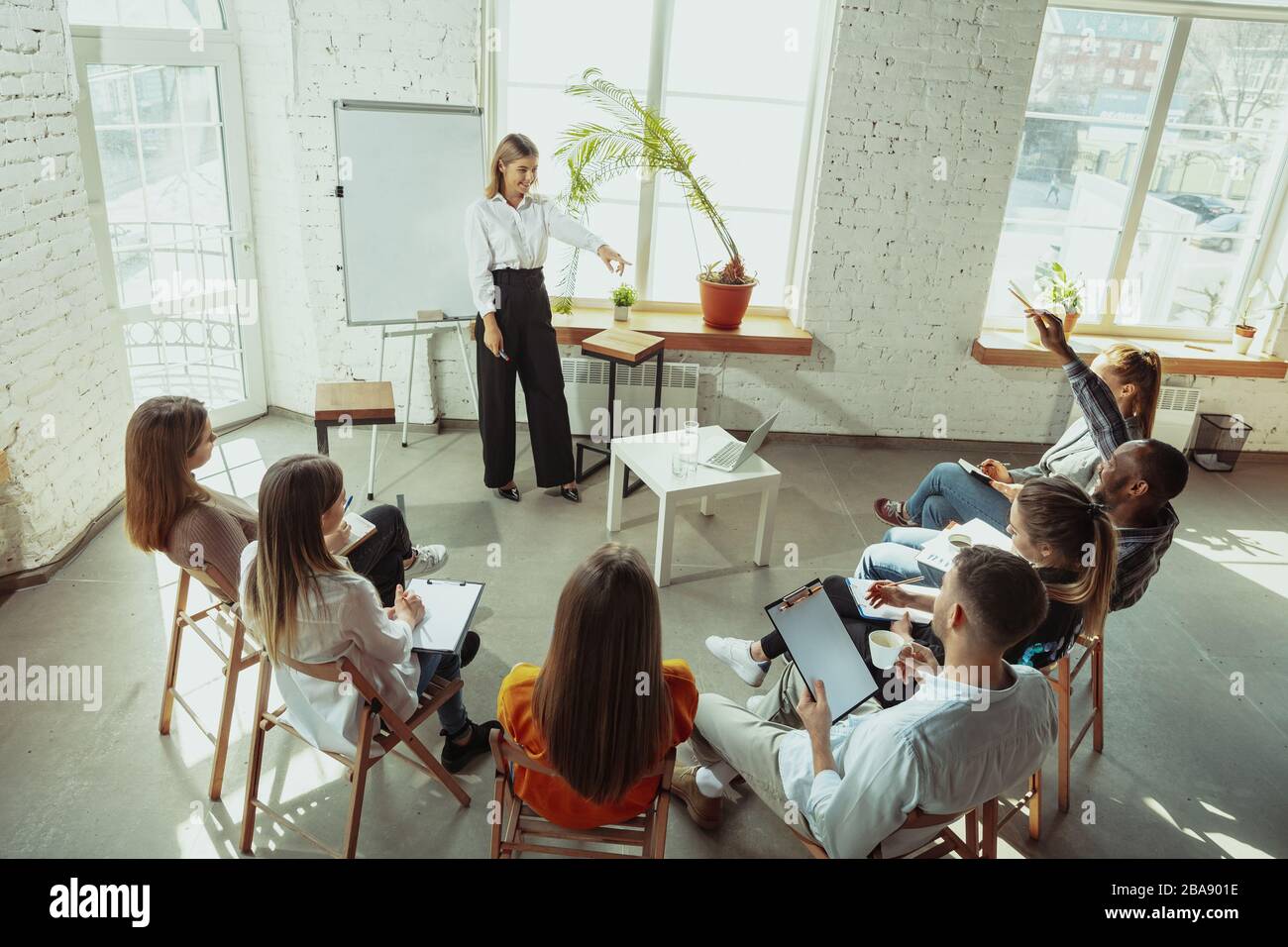 Giving information. Female speaker giving presentation in hall at ...