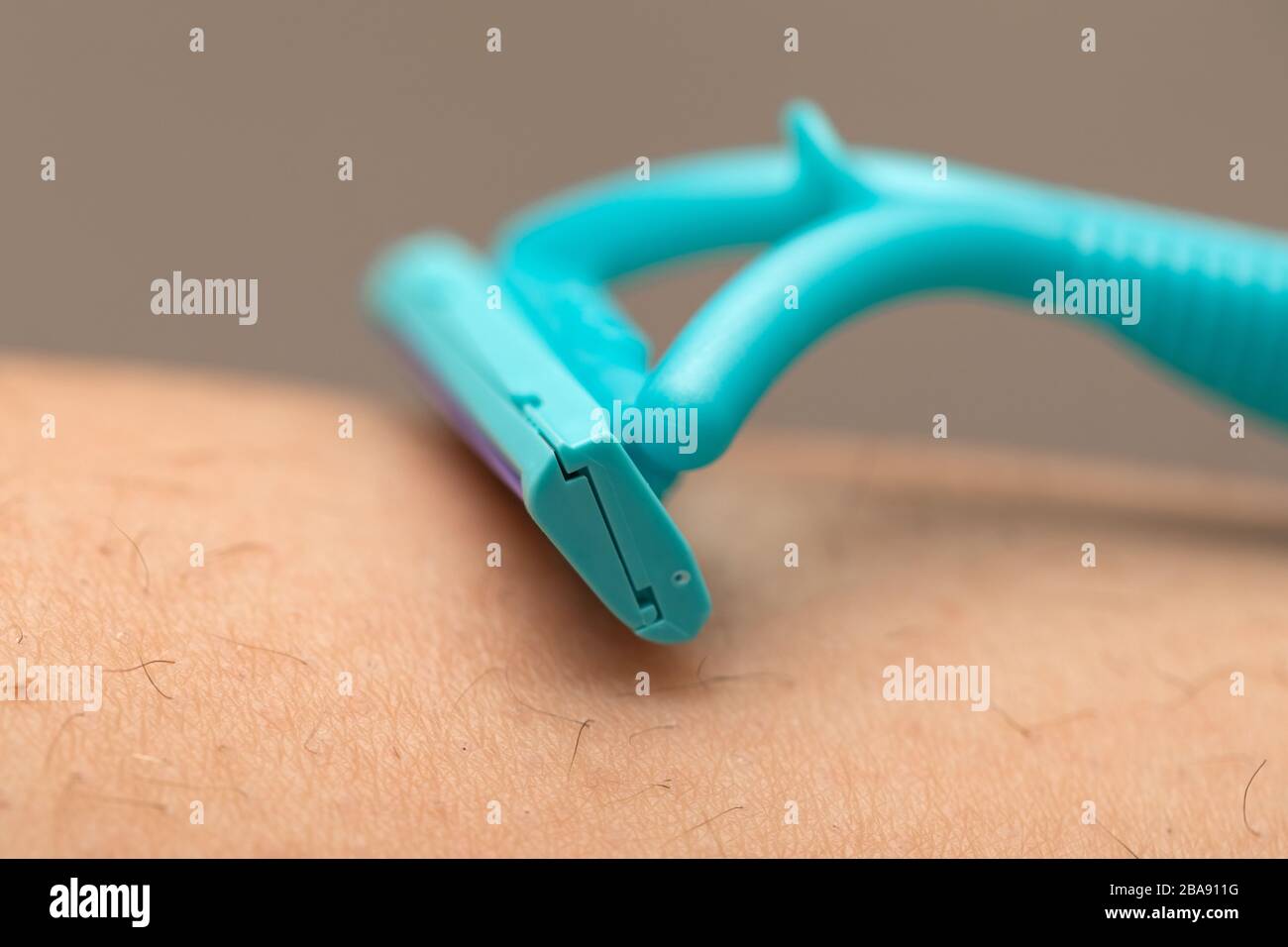Close up picture of woman holding razor, shaving her hairy leg with ...