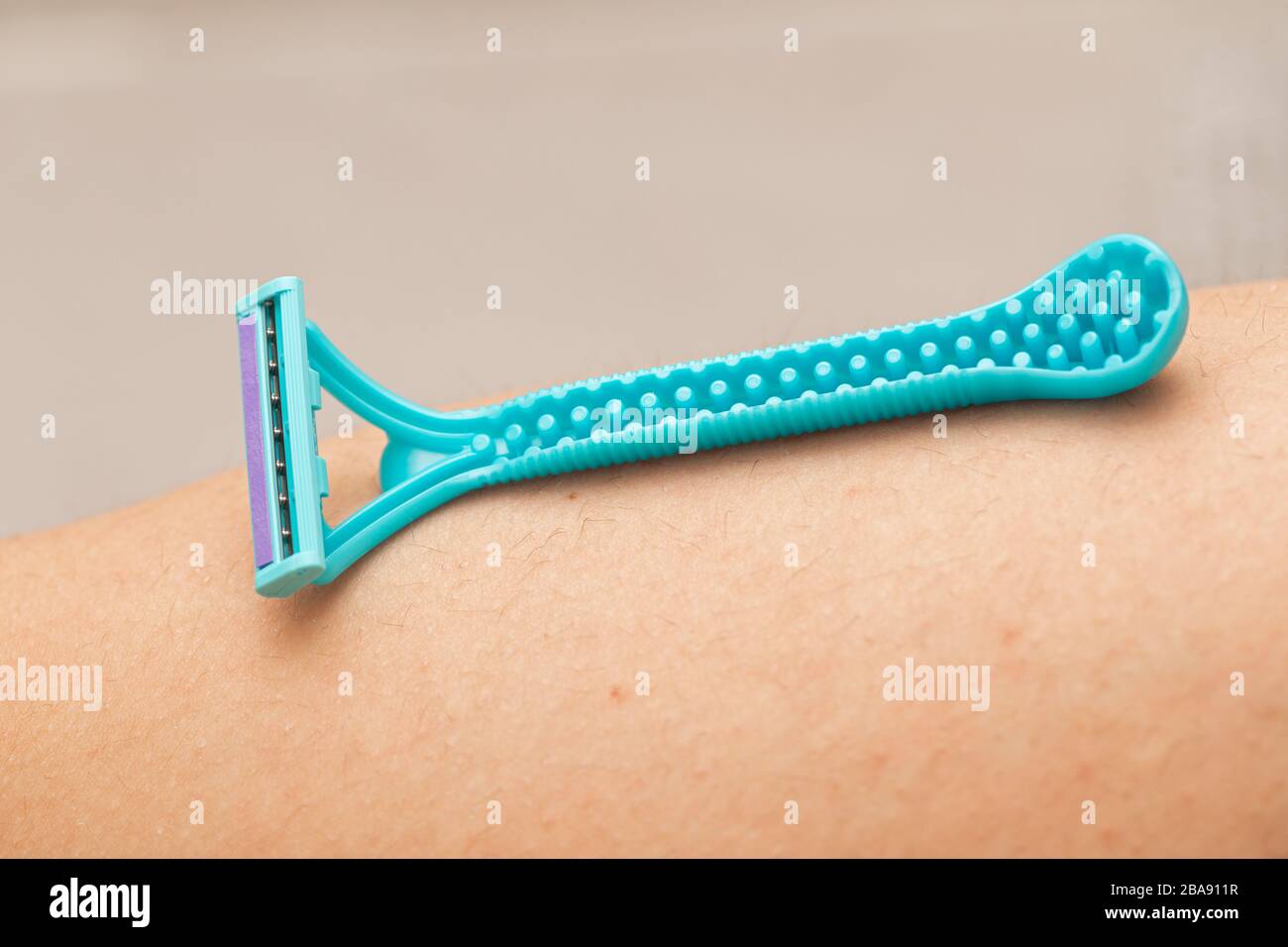 Close up picture of woman holding razor, shaving her hairy leg with ...