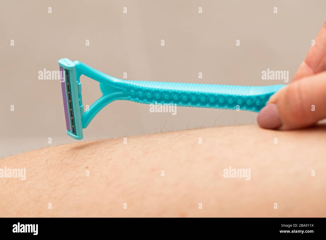 Close up picture of woman holding razor, shaving her hairy leg with ...