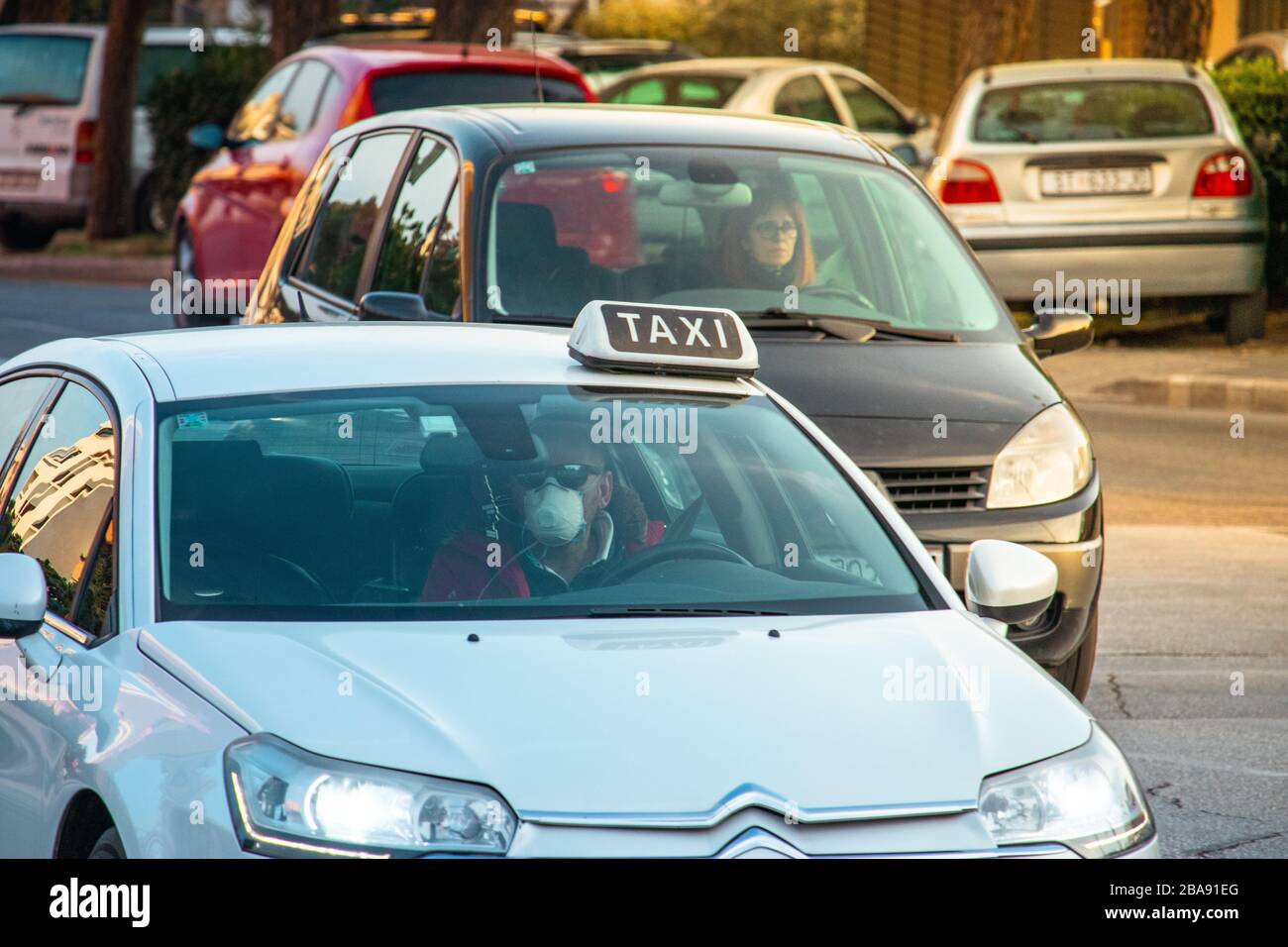 Taxi driver in a white citroen wearing a protective face mask during ...