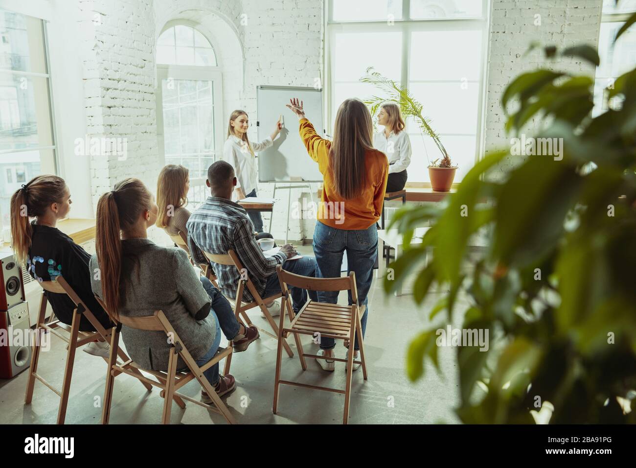 Asking a question. Female speaker giving presentation in hall at ...