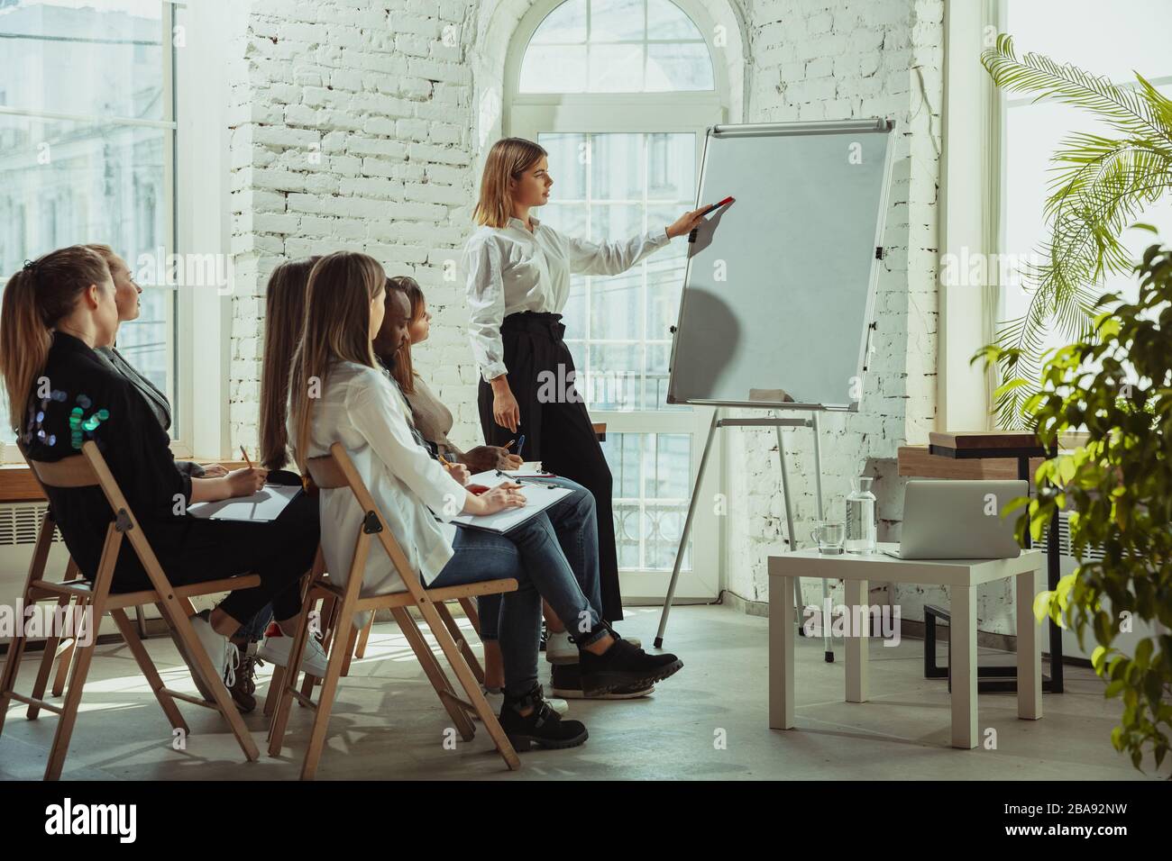 Lesson. Female speaker giving presentation in hall at workshop ...