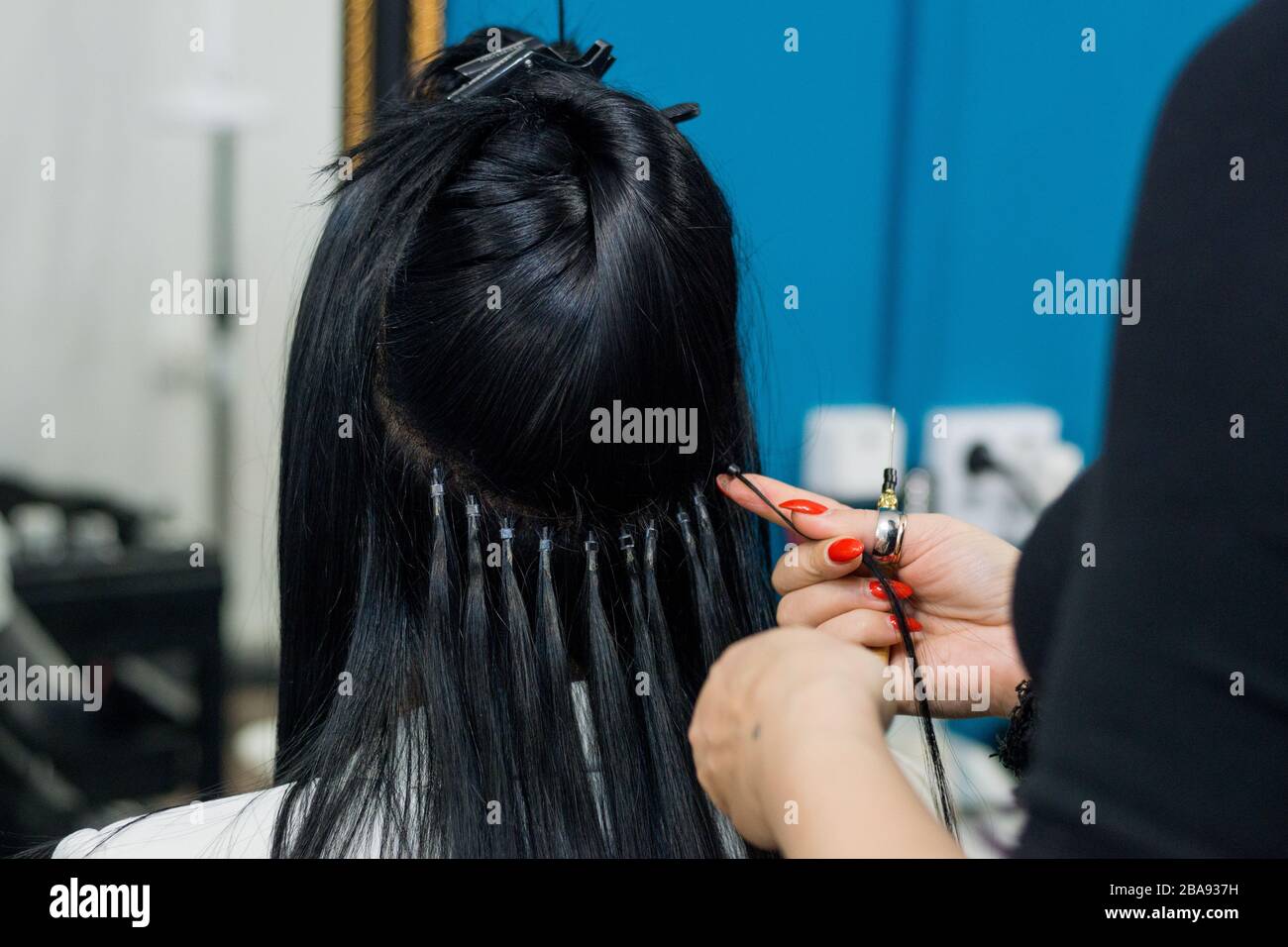 Professional woman applying hair extensions with different types of ...