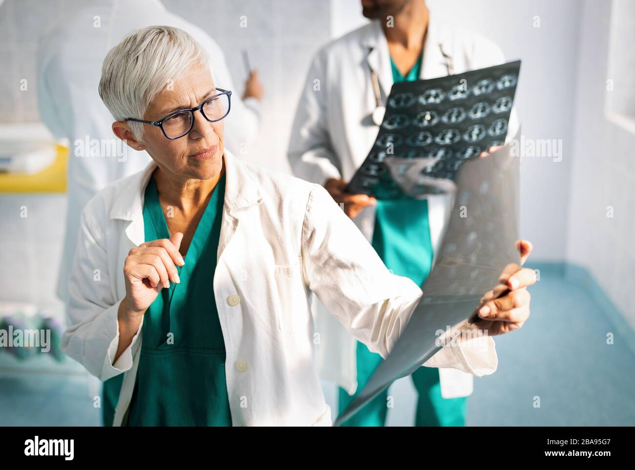 Doctors discussing patient's diagnosis looking at x-rays in a hospital ...