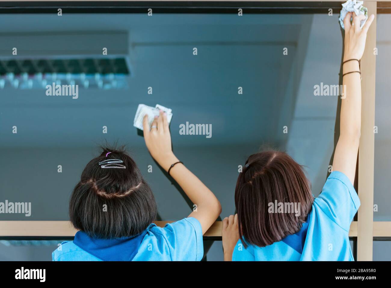 Back view of female students are helping to wipe the glass with wet ...