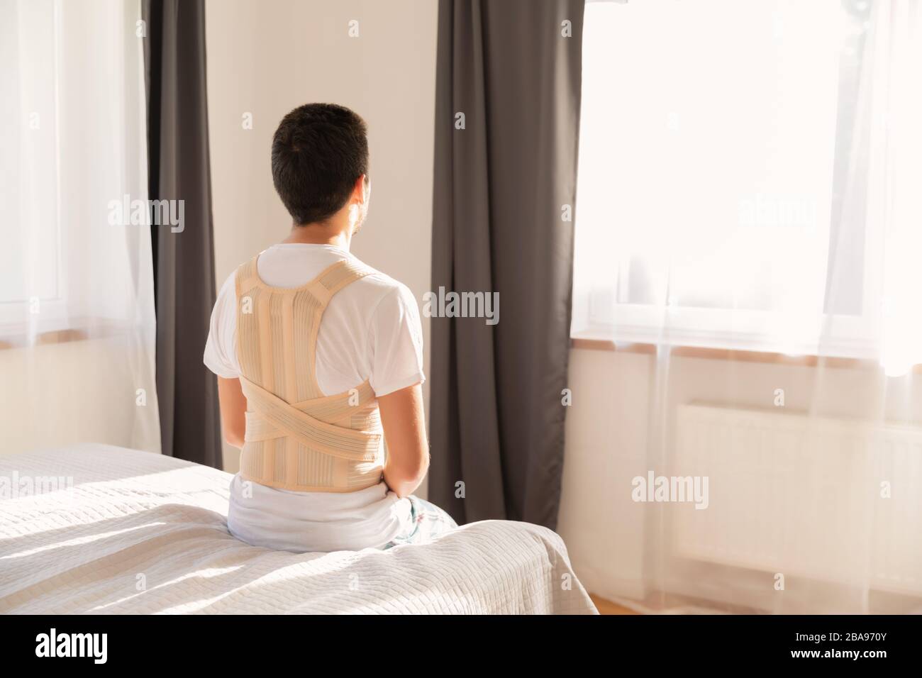 Young man wearing a back support belt. Lumbar brace, back support for ...