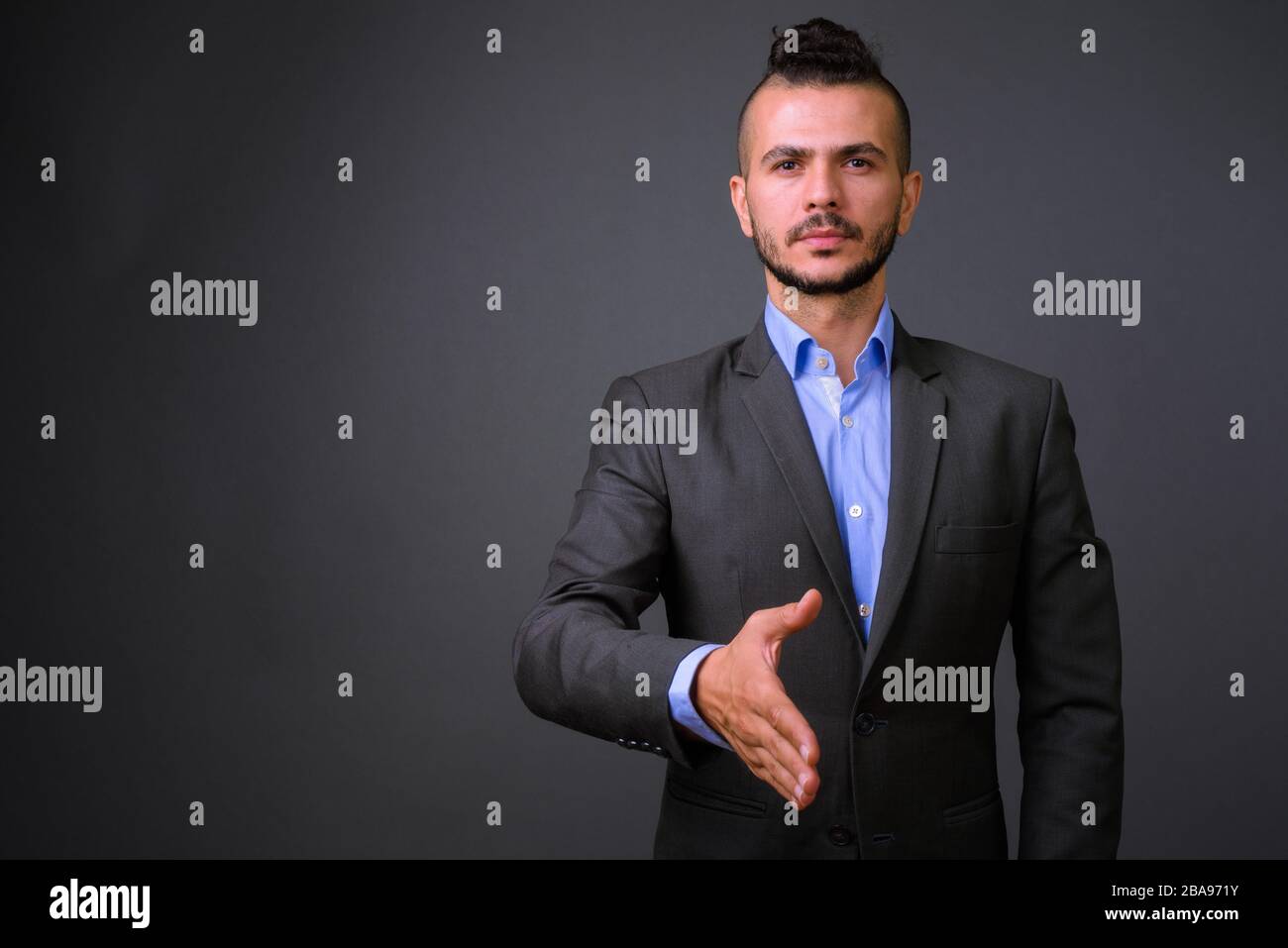 Portrait of handsome bearded Turkish businessman in suit giving ...