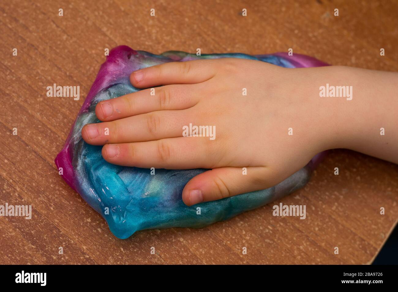 kid playing with slime on wooden table Stock Photo - Alamy