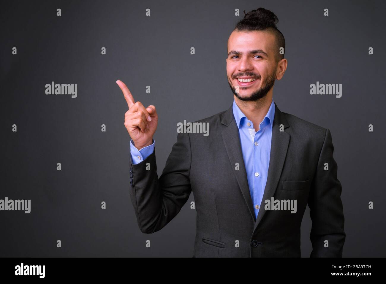 Portrait of happy bearded Turkish businessman in suit pointing up Stock ...
