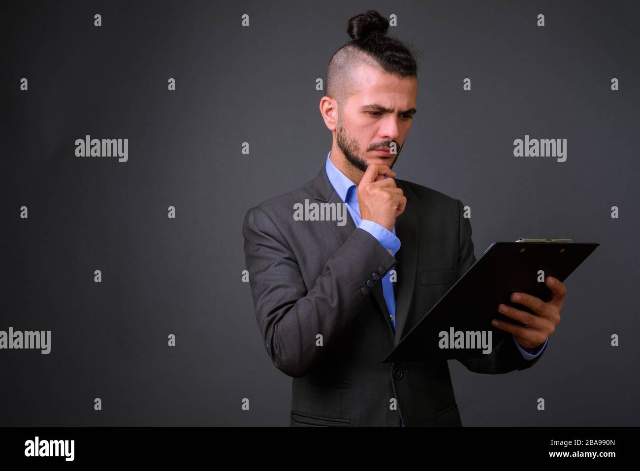 Portrait of handsome bearded Turkish businessman in suit reading on ...