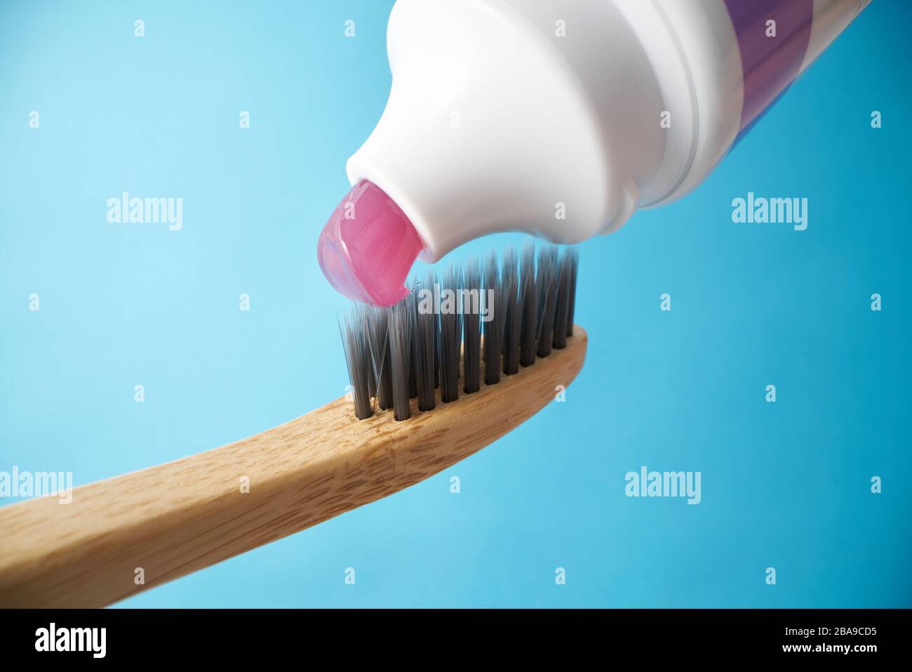 Pink toothpaste on a natural bamboo toothbrush with black charcoal ...