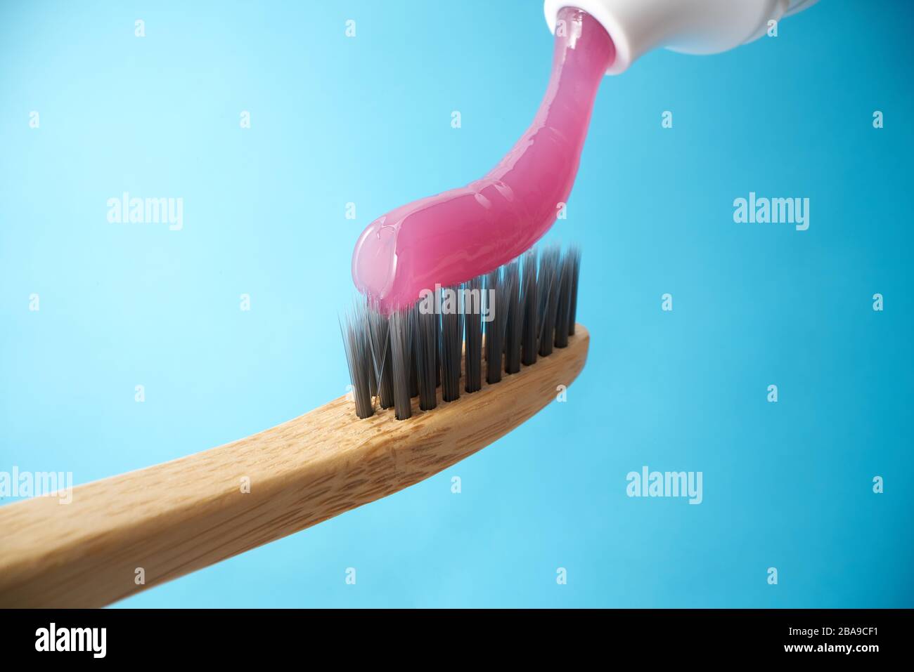 Pink toothpaste on a natural bamboo toothbrush with black charcoal ...