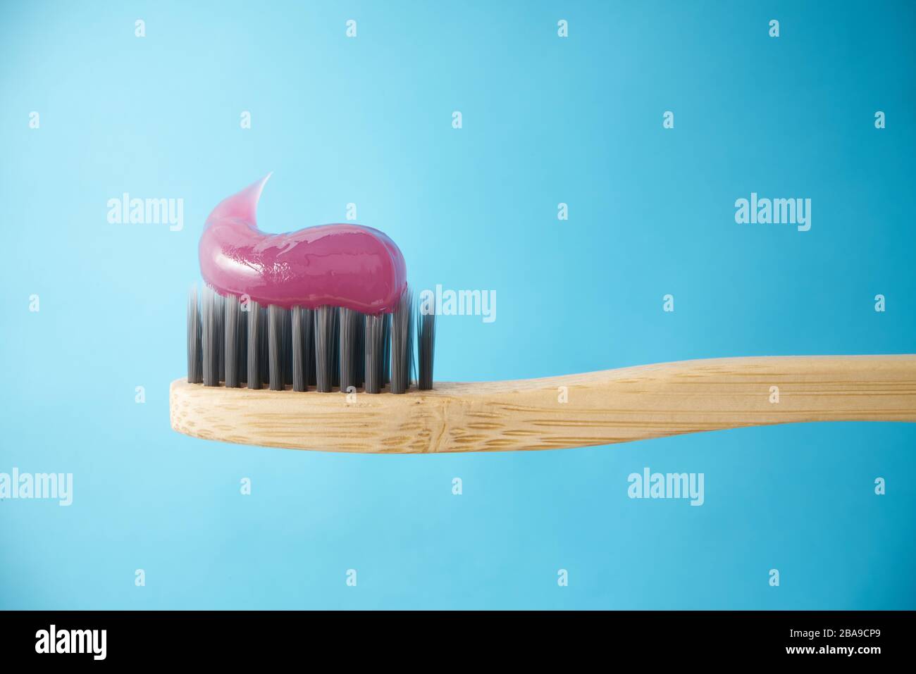 Pink toothpaste on a natural bamboo toothbrush with black charcoal ...