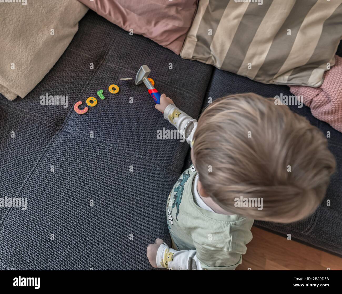 Corona virus. A little boy hammers the CORONA letters with a hammer ...