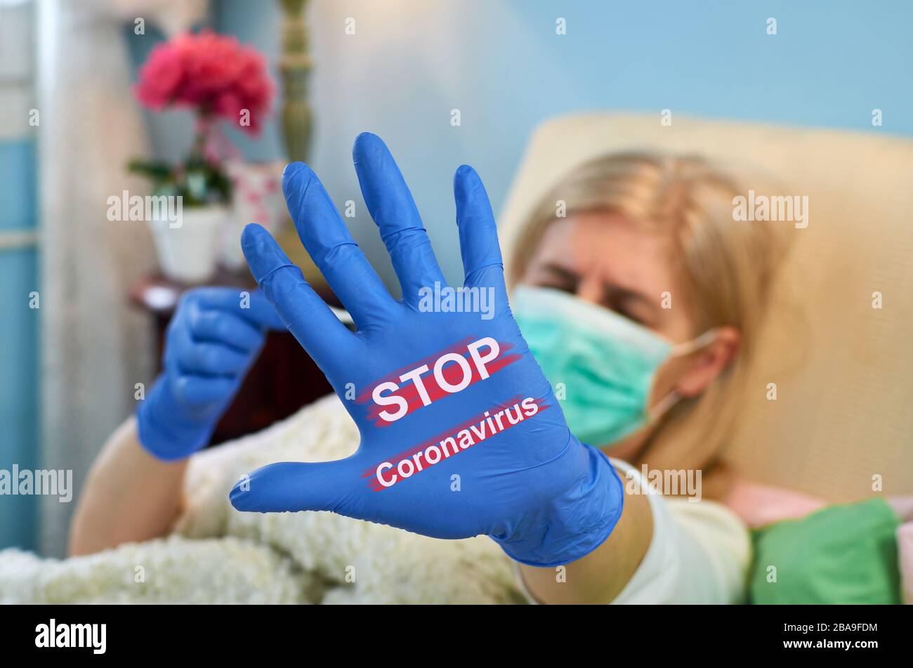 Sick woman lying in a bed with a raised hand showing to step away ...