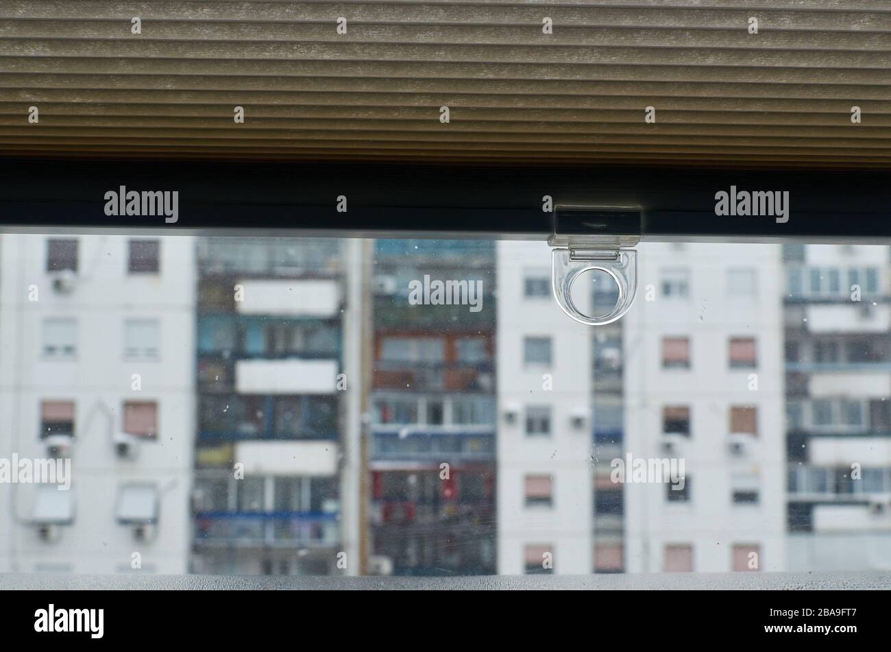 View through a window with a half raised blind to a next residential ...