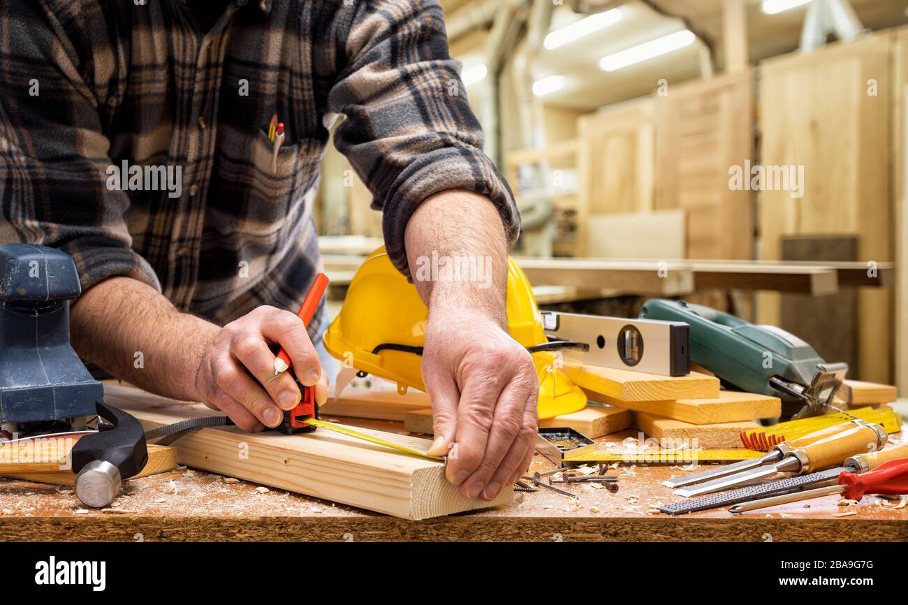 Close-up. Carpenter with pencil and the meter marks the measurement on ...