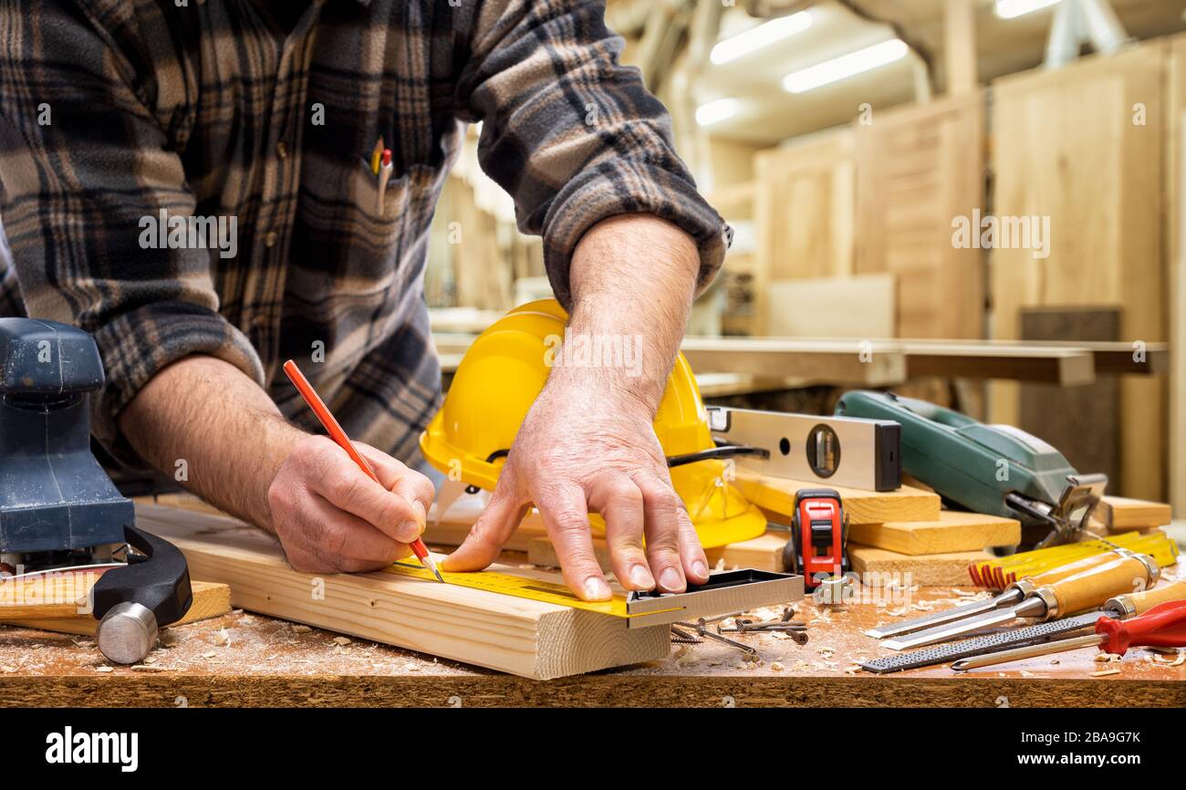 Close-up. Carpenter with pencil and carpenter's square draw the cutting ...
