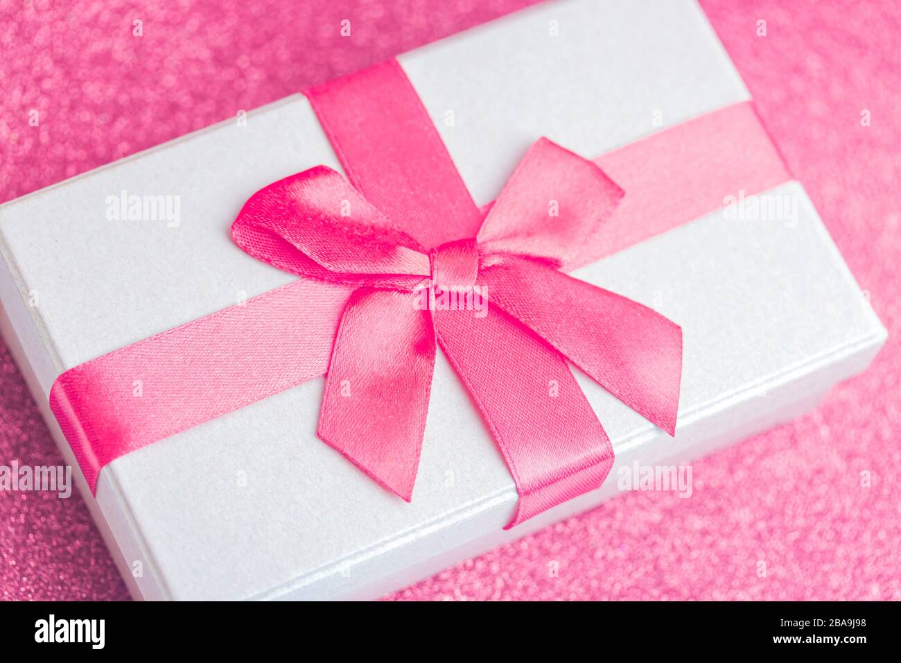 Present paper box with pink bow on glitter background Stock Photo - Alamy