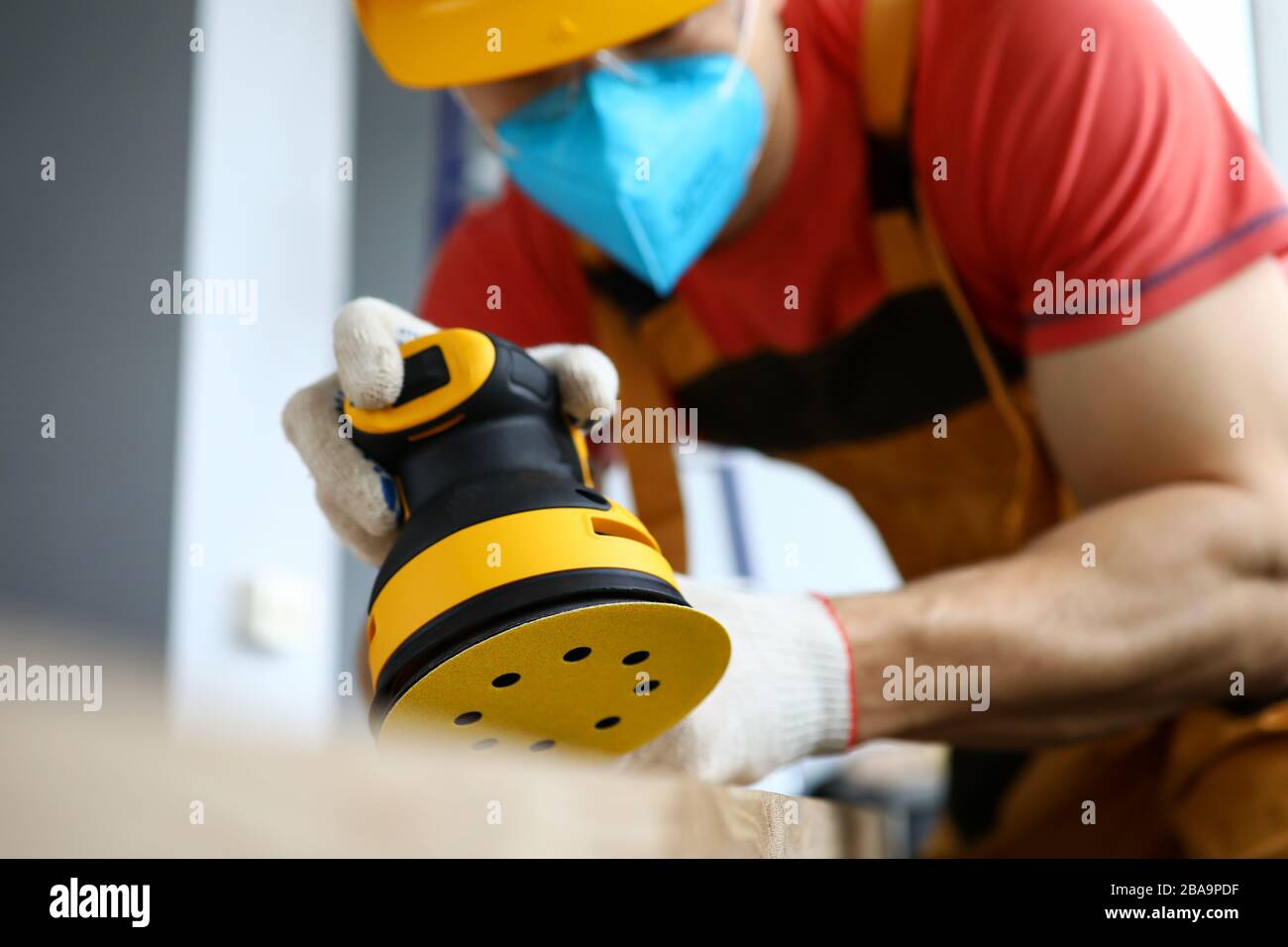 Male construction worker wearing hardhat and protective mask using ...