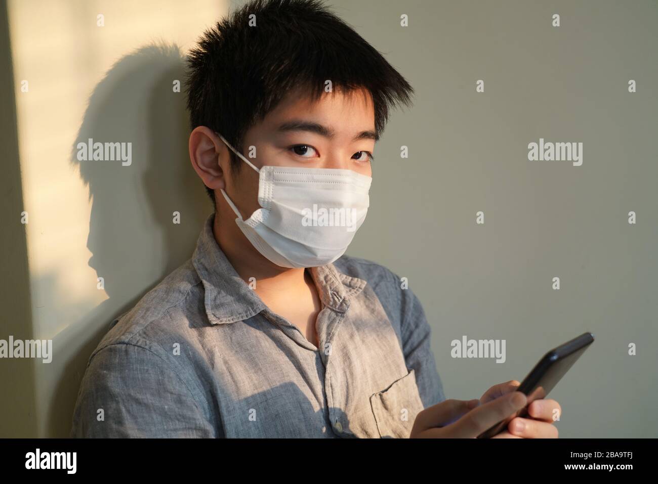 Wearing a mask of the boy see a mobile phone Stock Photo - Alamy