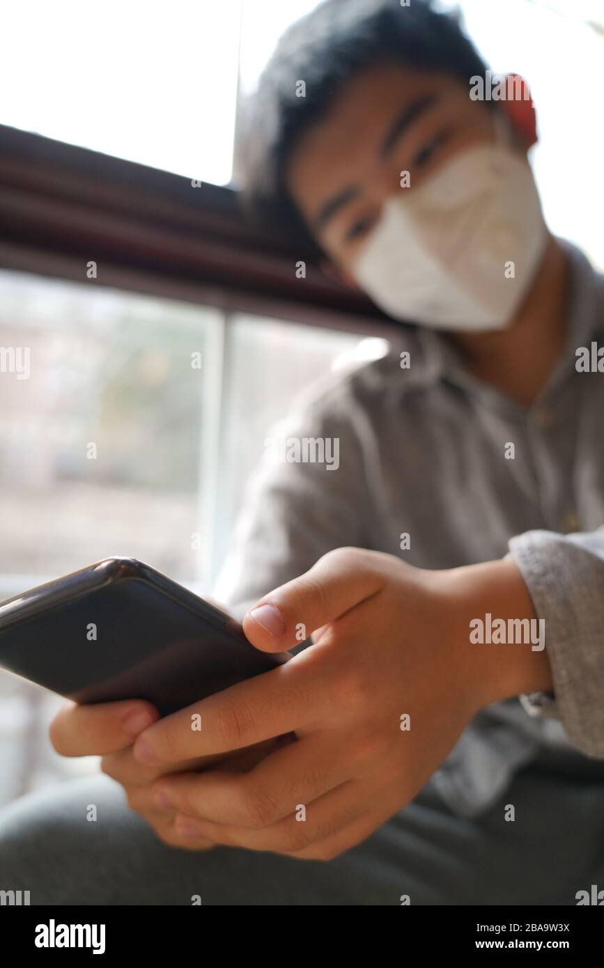 Wearing a mask of the boy see a mobile phone Stock Photo - Alamy