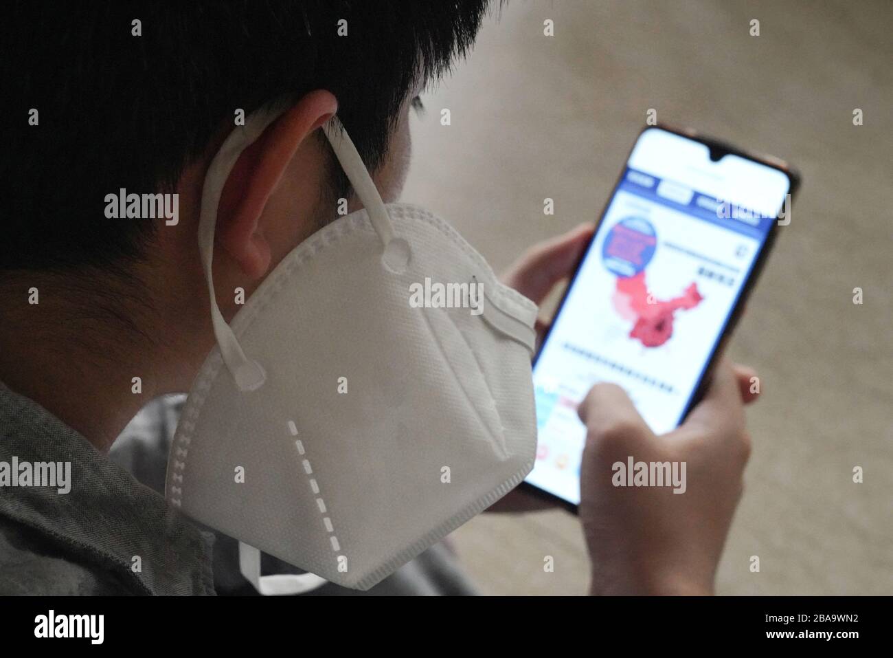Wearing a mask of the boy see a mobile phone Stock Photo - Alamy