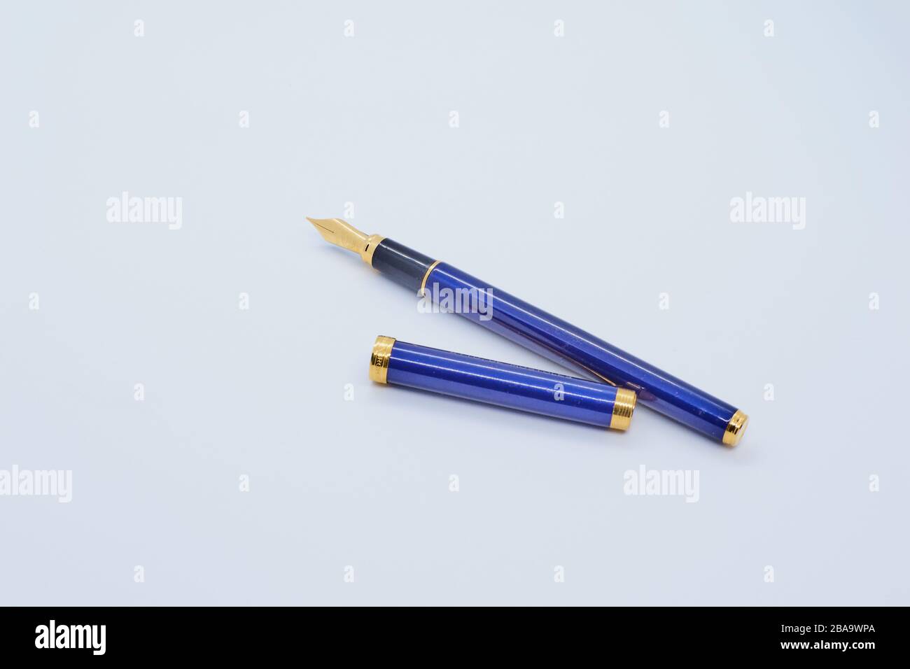 A blue and golden fountain Pen with its lid on white background Stock ...