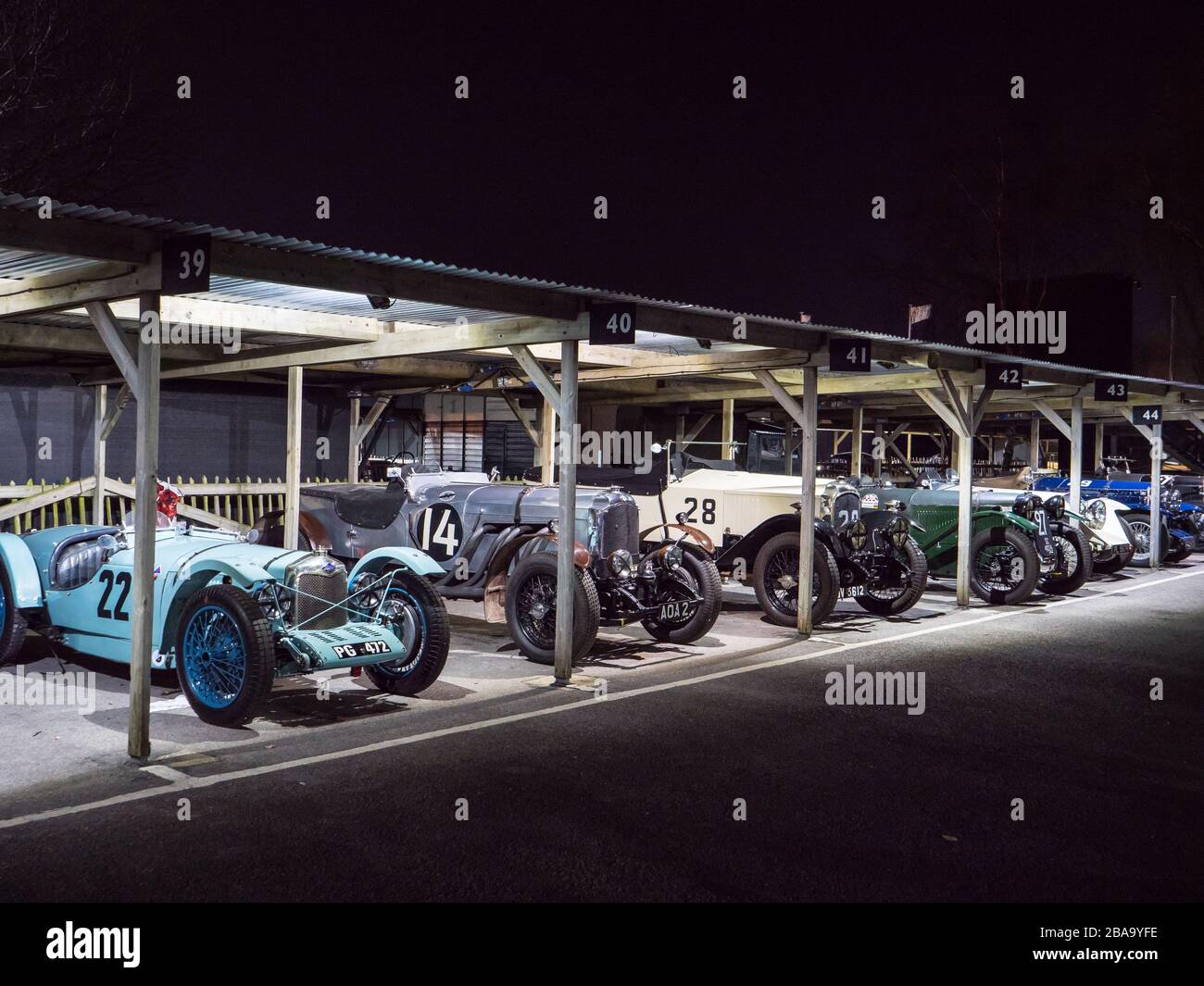 Vintage Edwardian racing cars parked in the paddock area at night, at ...
