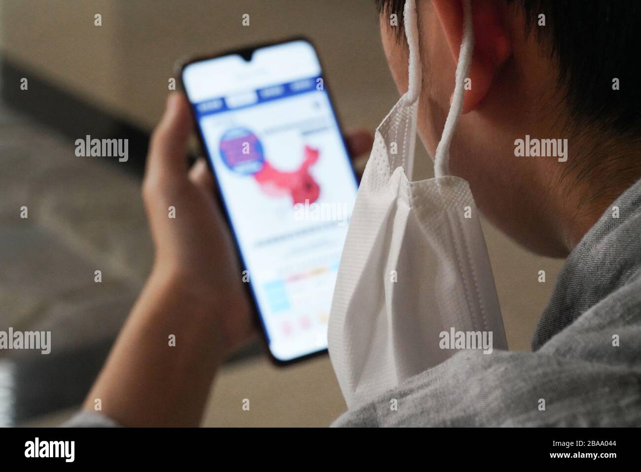 Wearing a mask of the boy see a mobile phone Stock Photo - Alamy