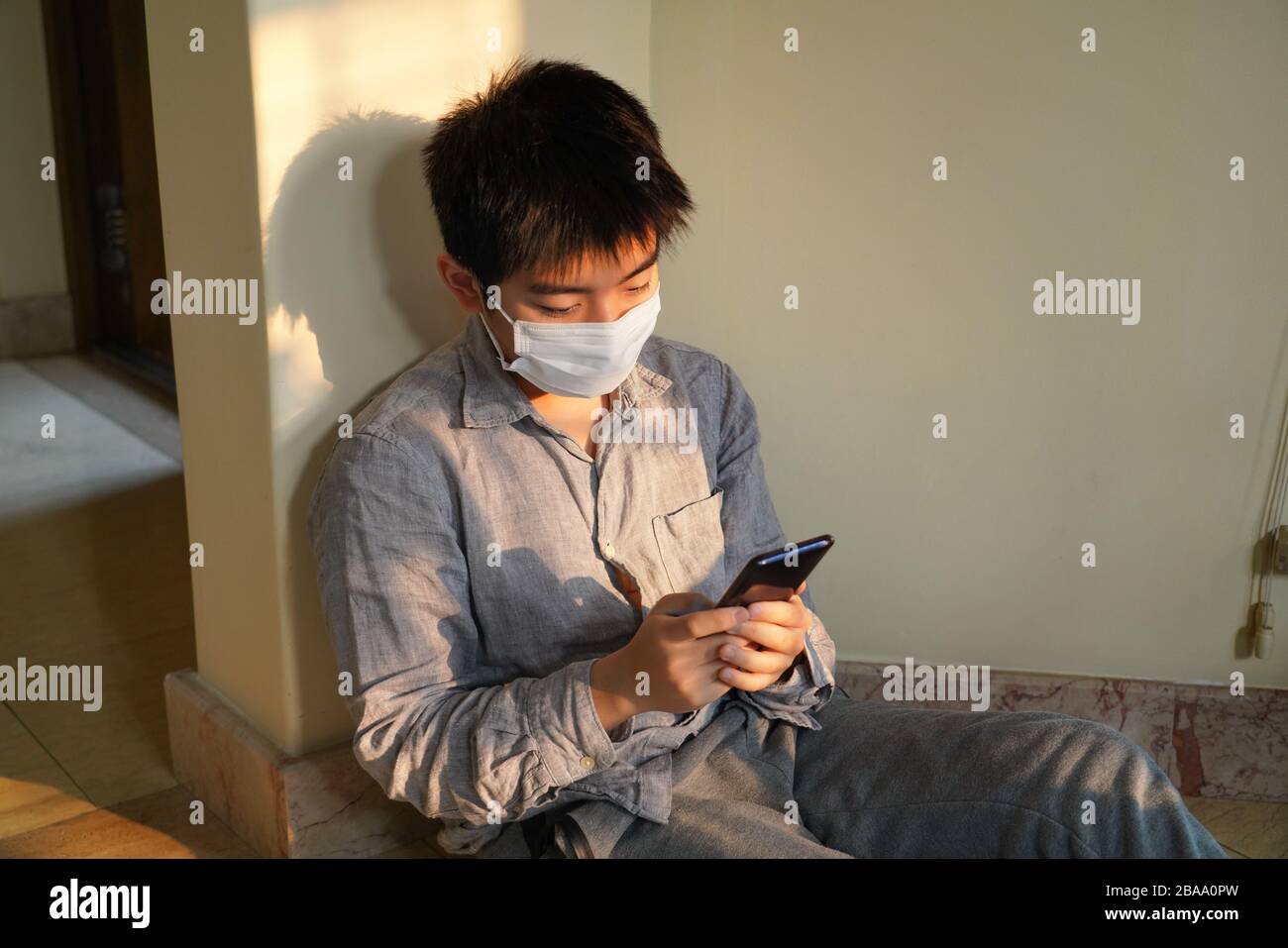 Wearing a mask of the boy see a mobile phone Stock Photo - Alamy