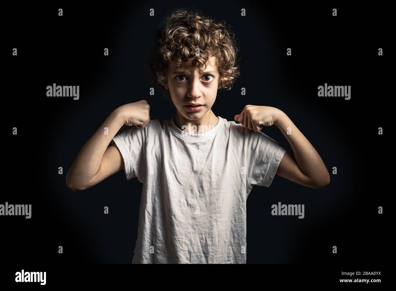 Body builder kid showing his little muscle with a a funny grimace face ...