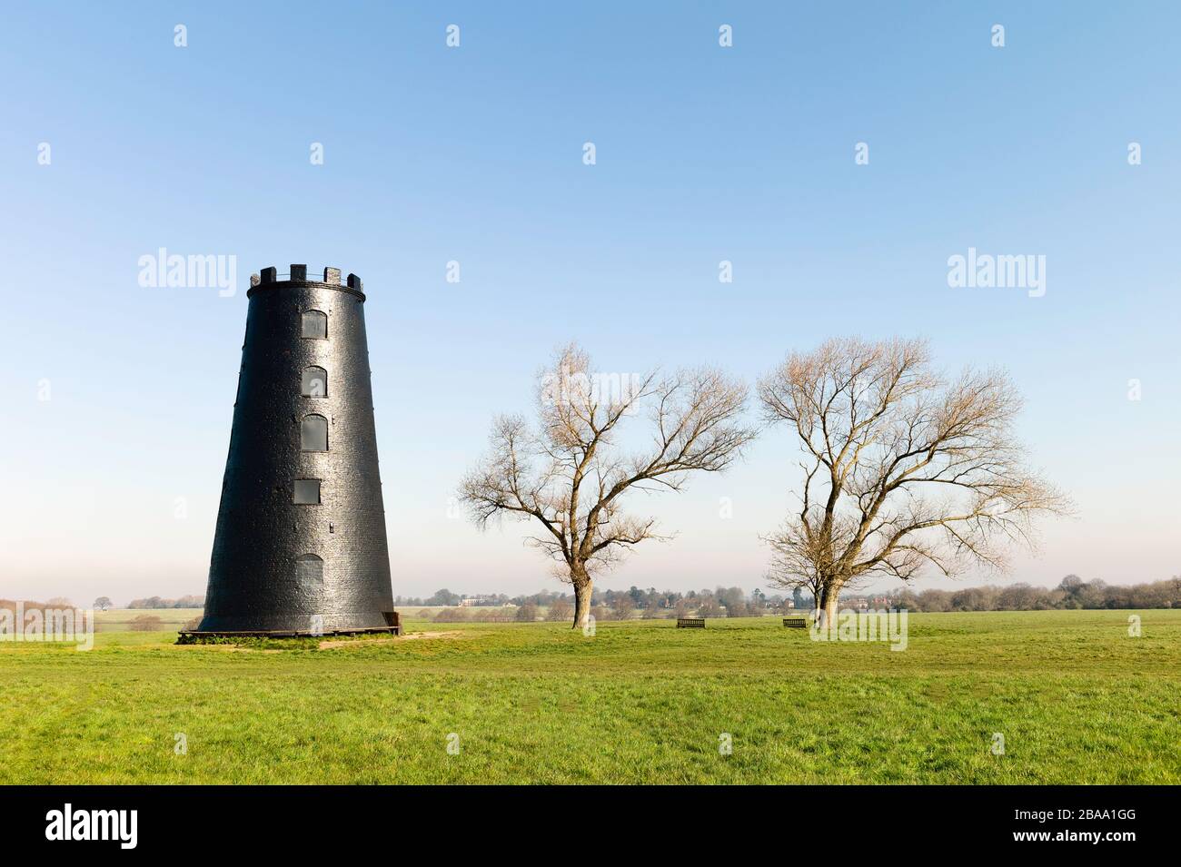 Black Mill, a local landmark, flanked by leafless trees under blue sky ...