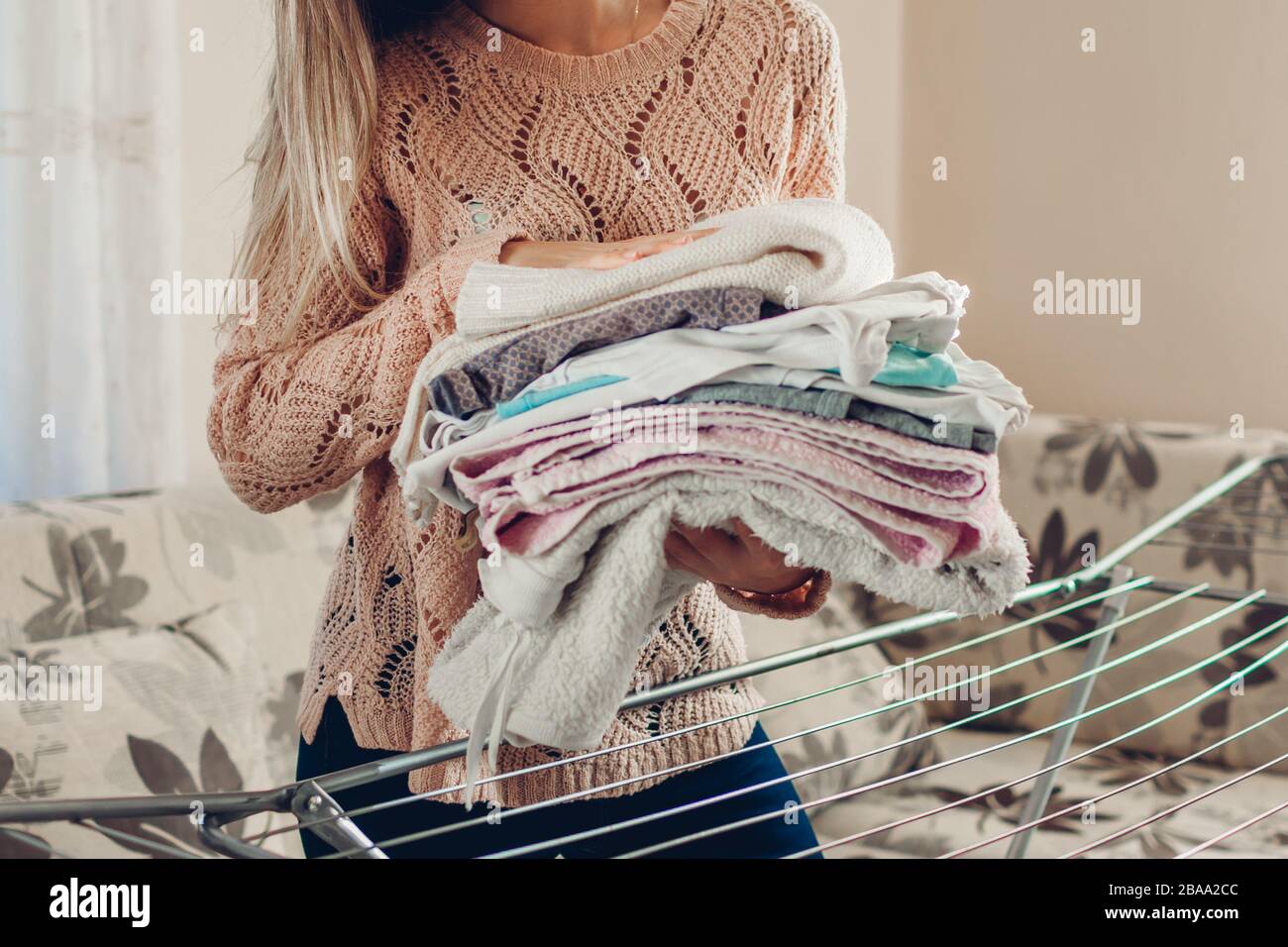 Happy woman housewife gathered clean clothes from dryer in heap ...