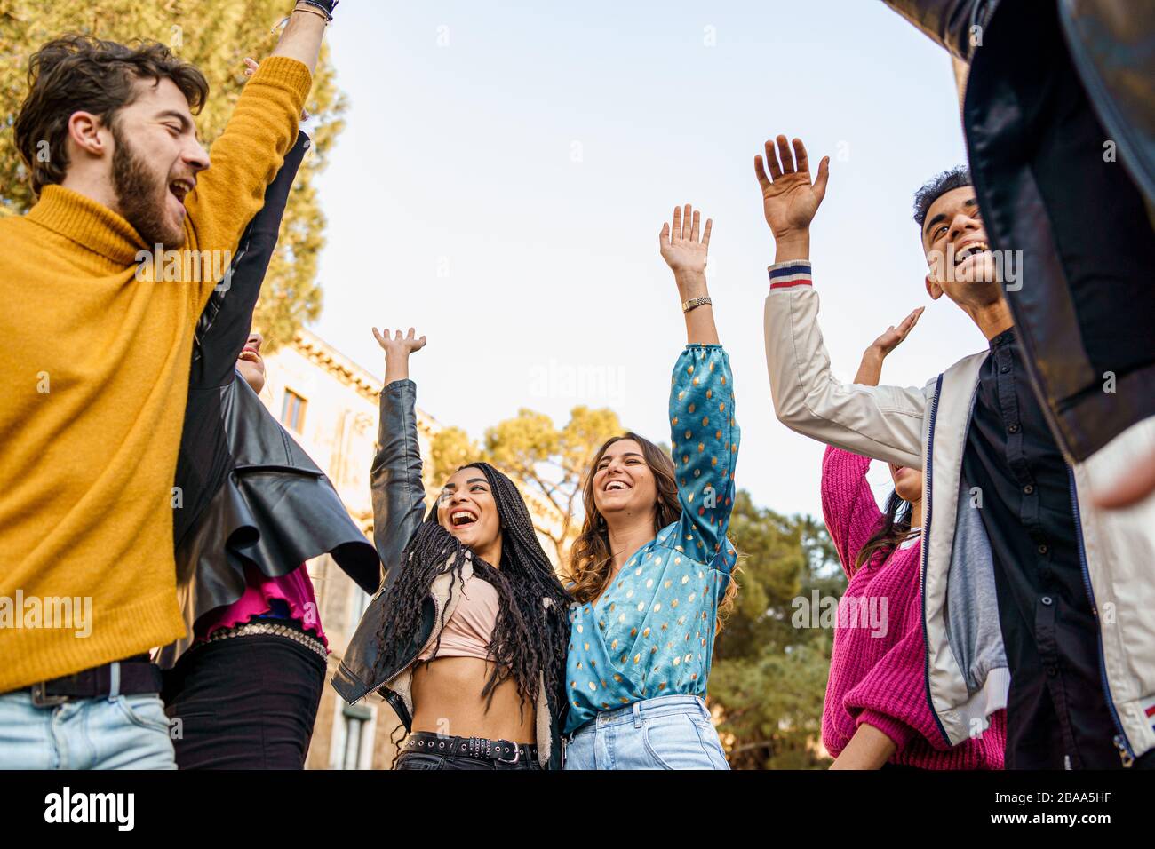 Joyful young people hands raised up. Group of multiracial people having ...