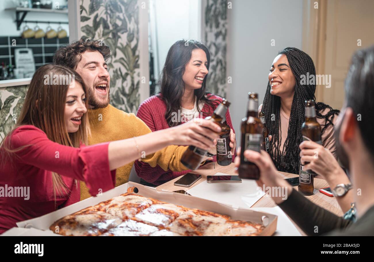 Group of young multiracial people clinking with beers indoors in front ...