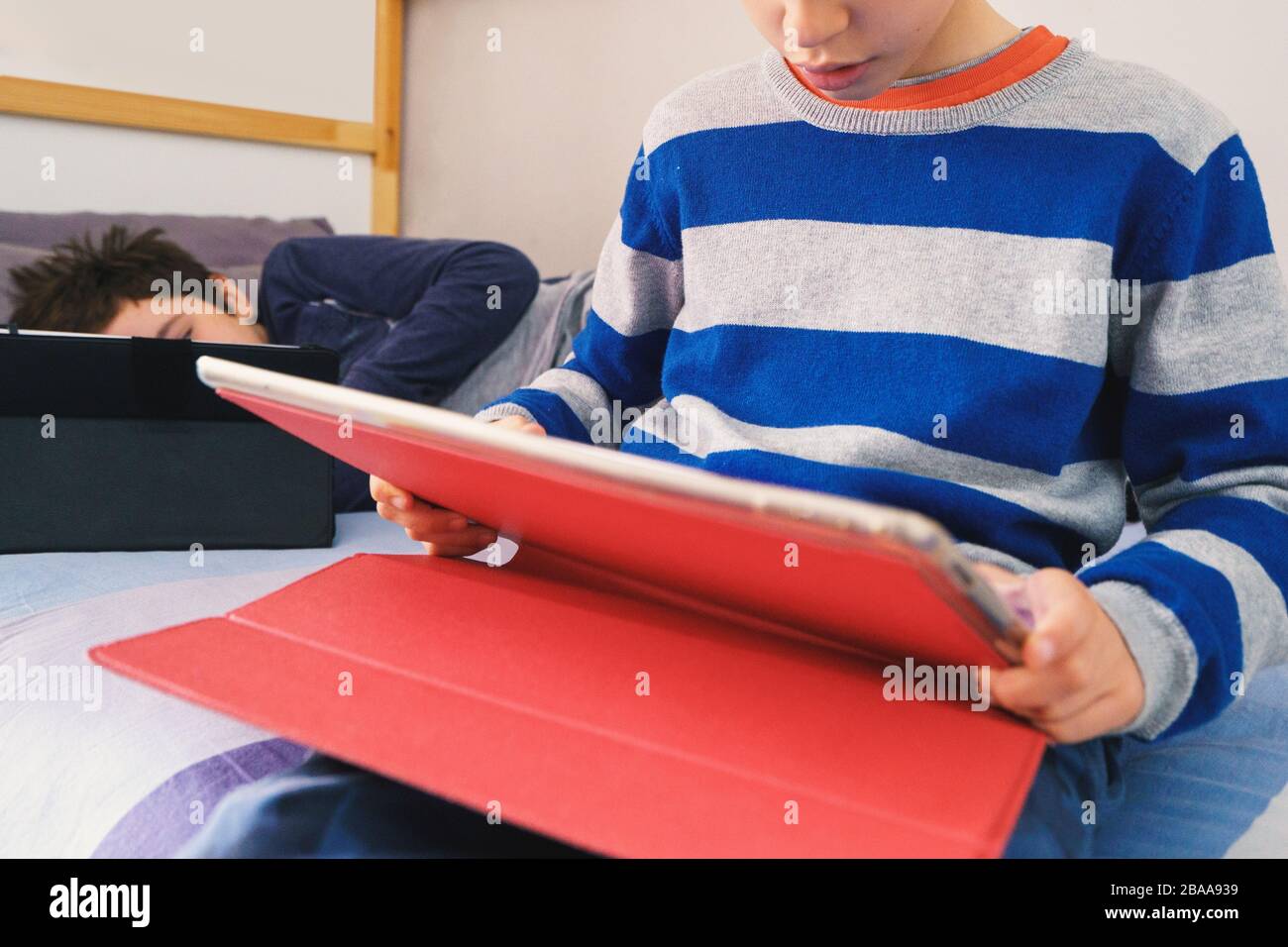 Kids playing with their tablets computers in their bedroom. Children ...
