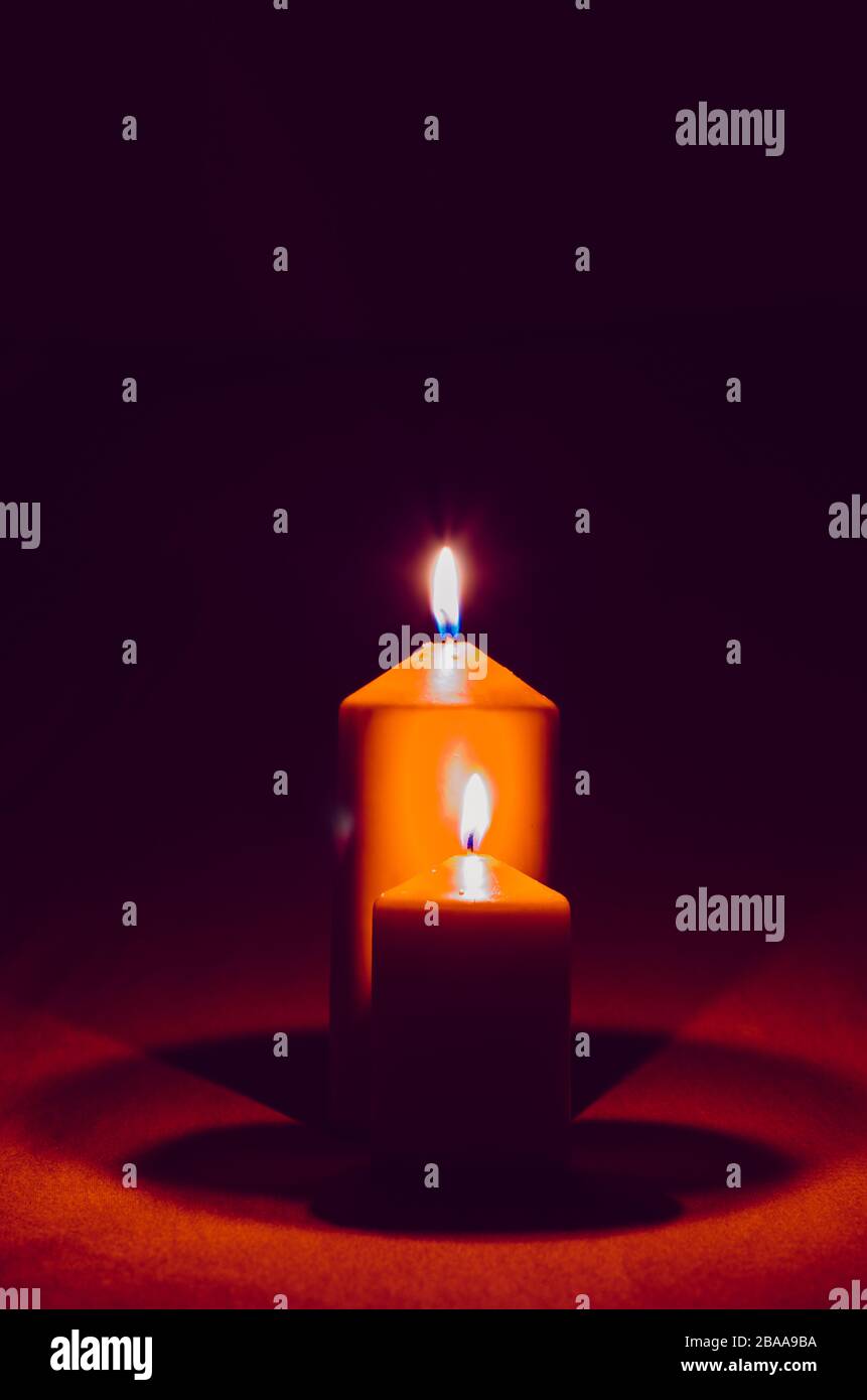 two red illuminated burning wax candles with black copy space ...
