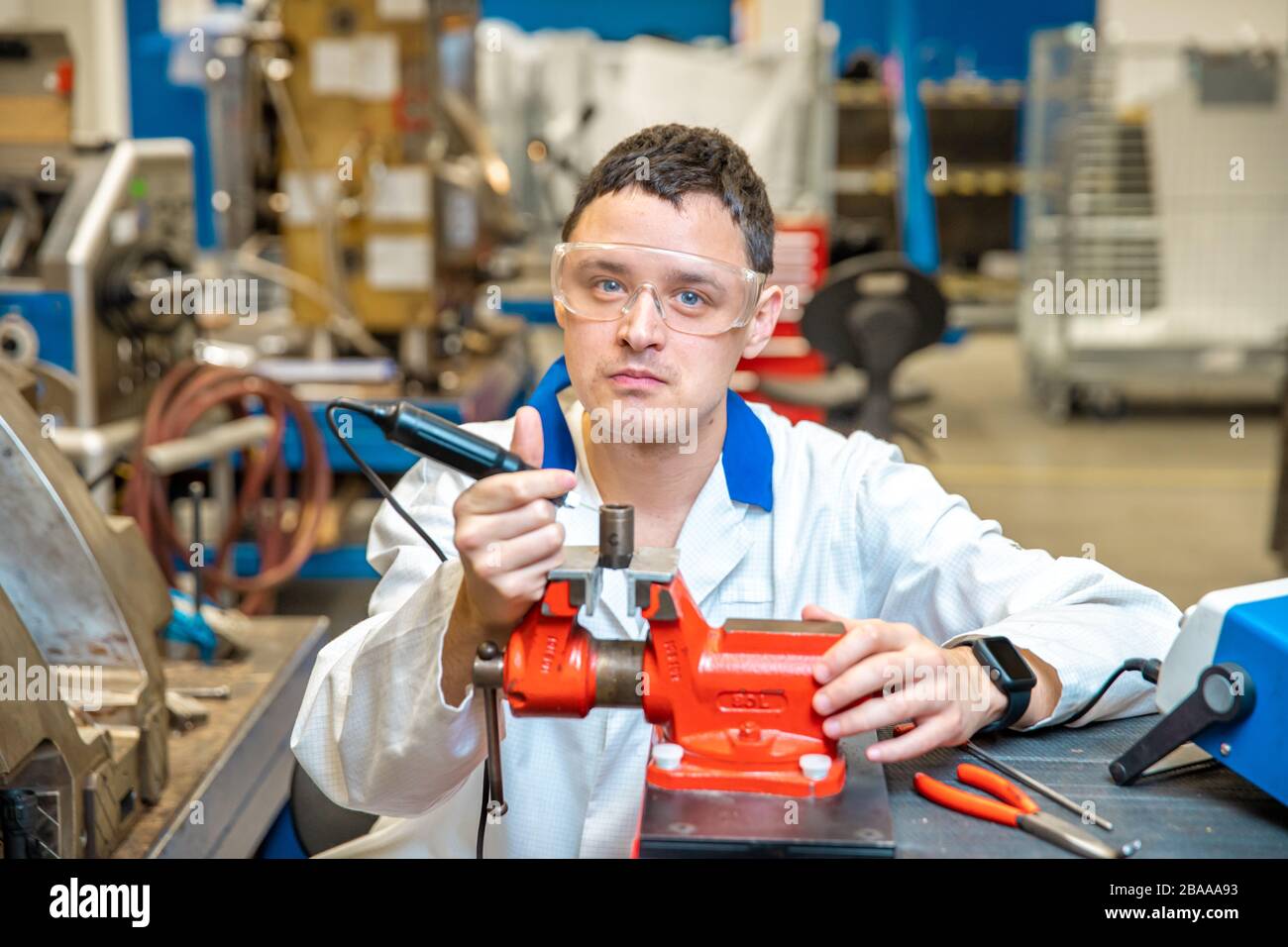worker in metal processing plant grinds metal component on vise Stock ...