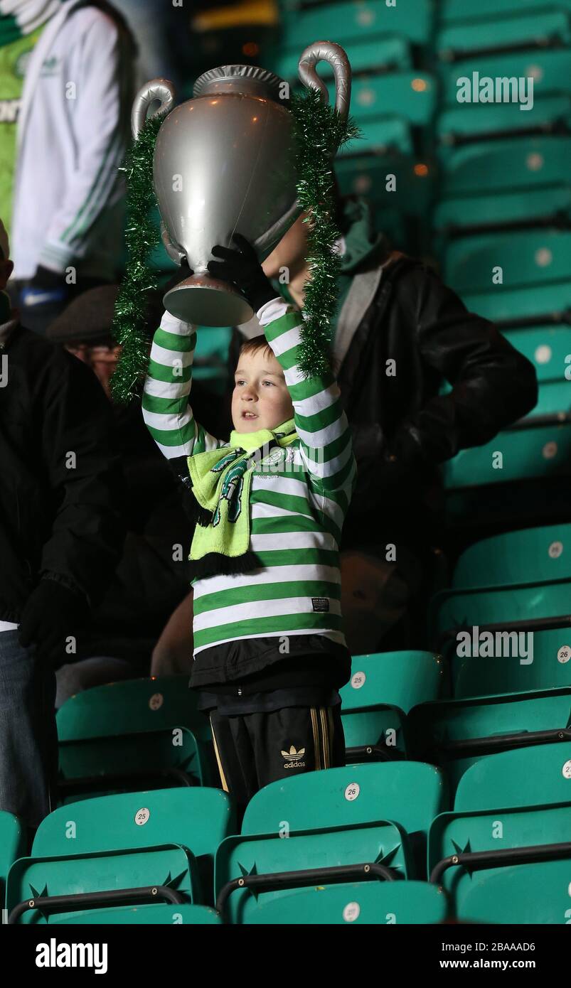 A young Celtic fan holds aloft a champions league trophy in the stands ...
