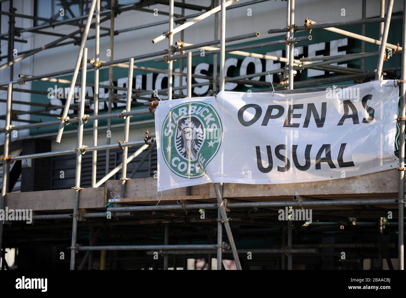View of a Starbucks covered in scaffolding with an open for business ...