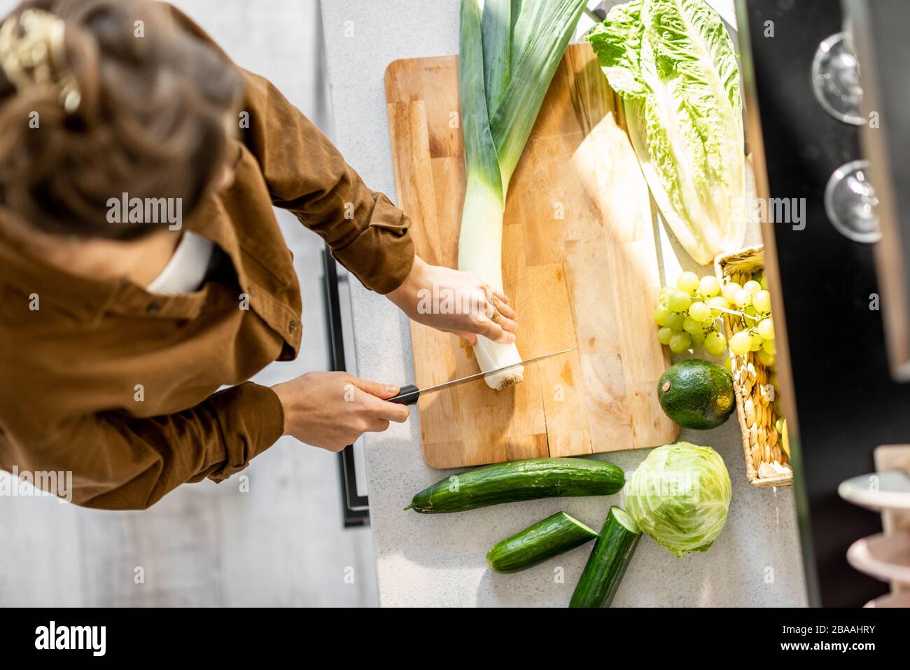 Woman cooking some food, cutting fresh ingredients on the cutting board ...