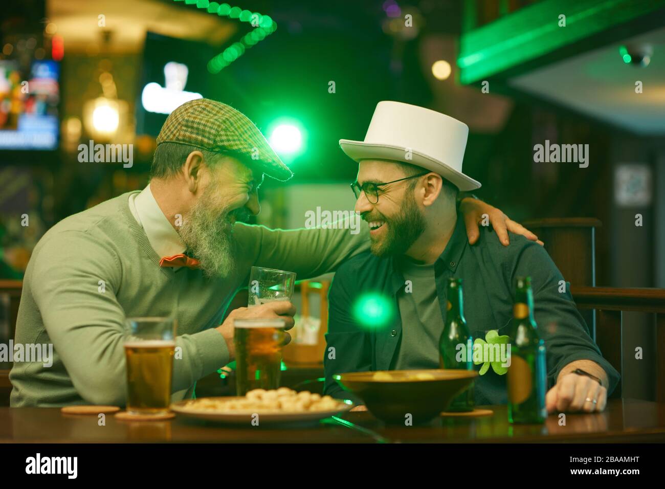 Two bearded men laughing and talking to each other while drinking beer ...