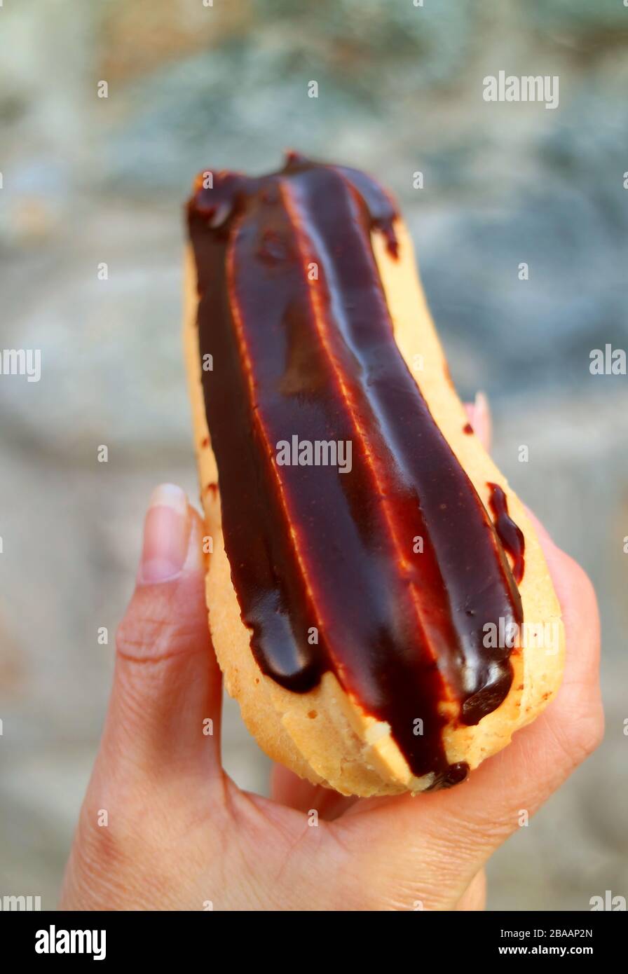 Vertical Image of a Tasty Chocolate Eclair in Hand Stock Photo - Alamy