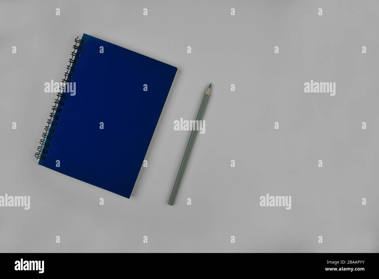 Silver colored wood pencil crayon placed beside a simple blue notebook ...