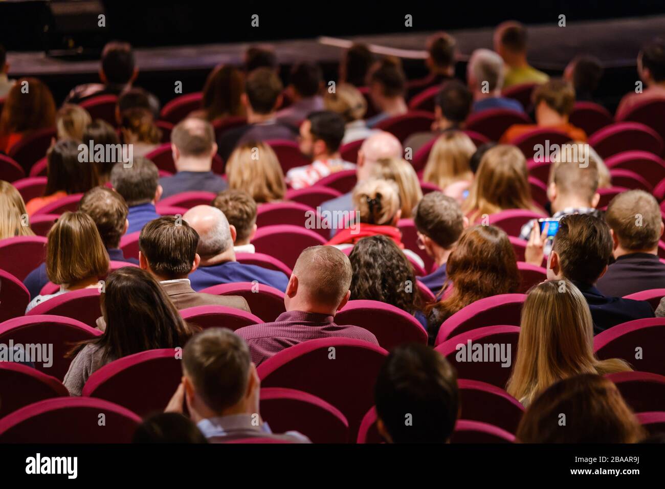 Business conference attendees sit and listen to lecturer, rear view ...